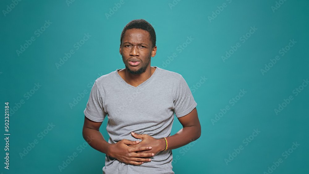 Portrait of male model having stomach ache and abdominal cramp, dealing ...