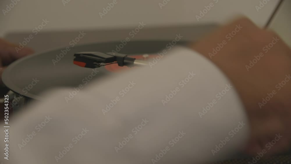 Hand stopping spinning record player. Lifting tonearm from turntable ...