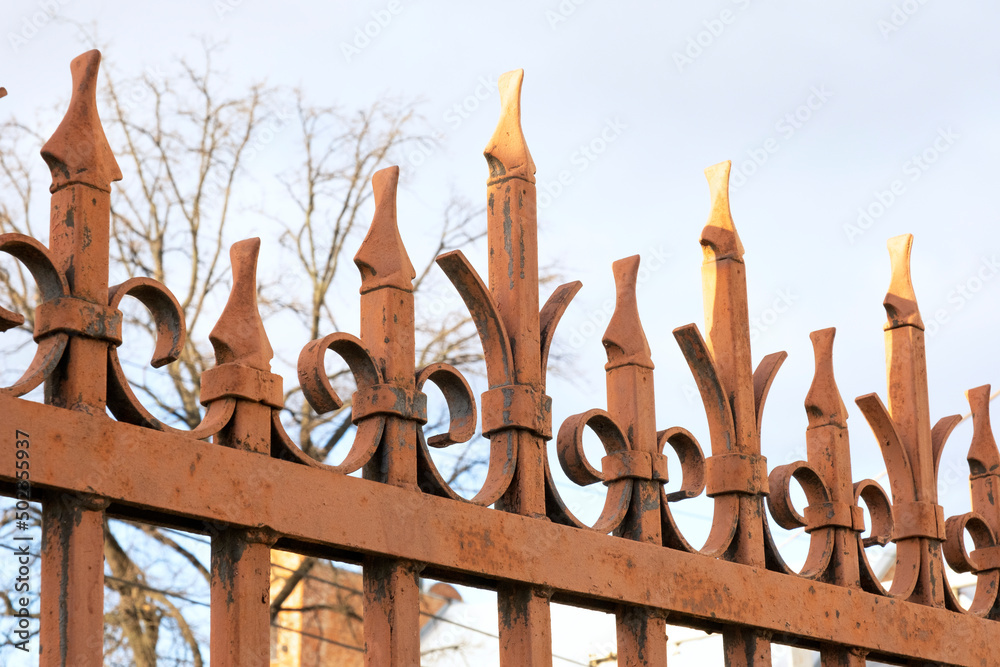 Spears on top of an old rusted metal fence. A rusted, decorated ...