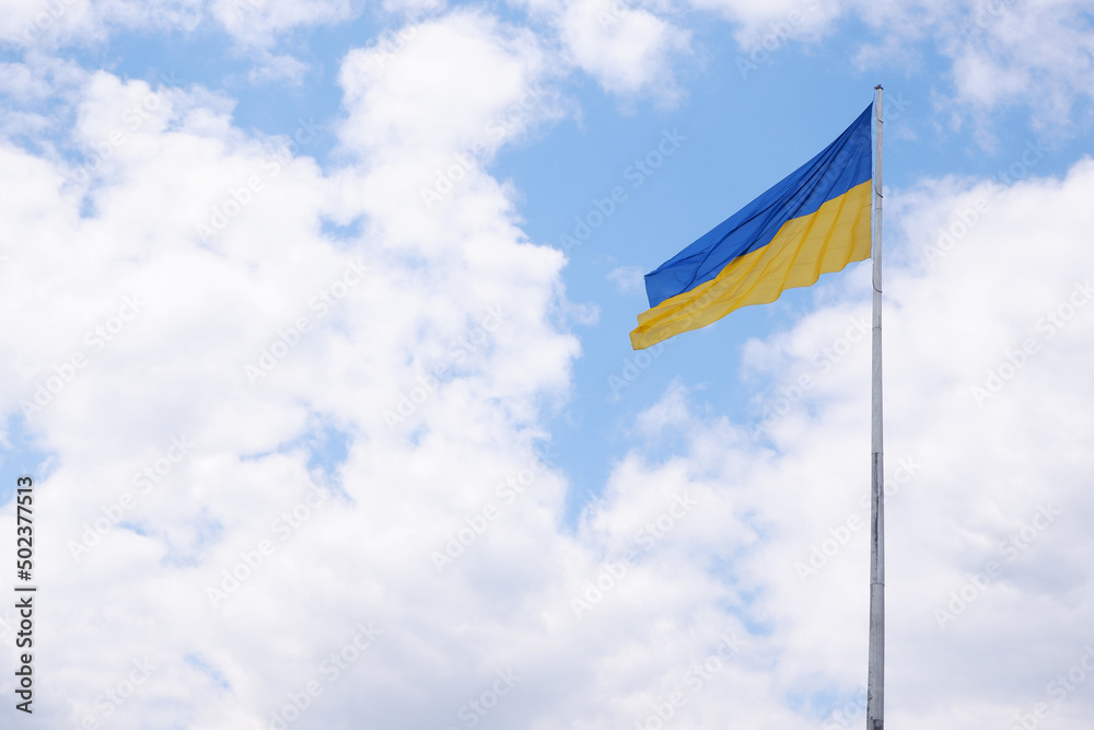 Flag of Ukraine on a high flagpole isolated on a blue sky background ...