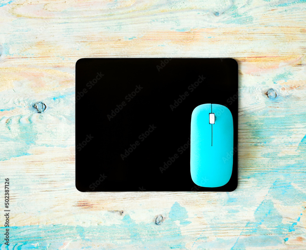 Black pad and blue computer mouse set on wooden colorful background ...