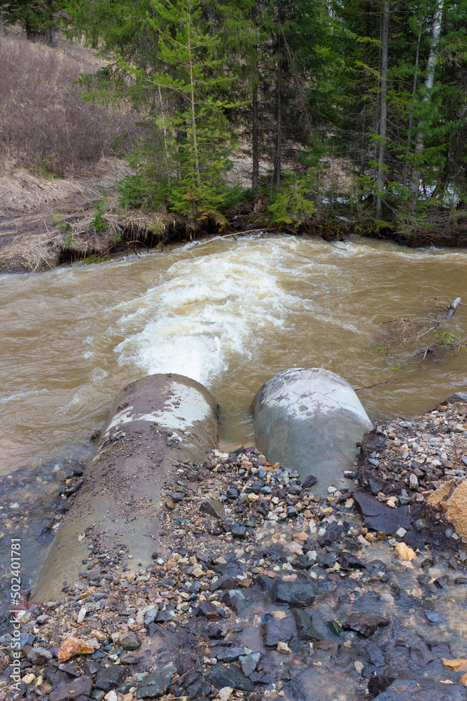 Two culvert under the forest road. A strong stream of water flows out ...