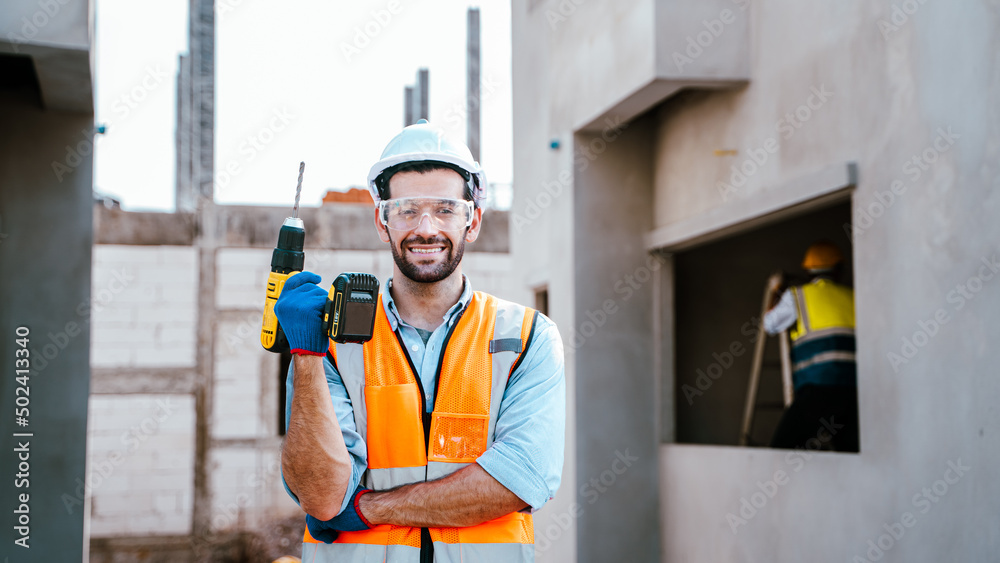 Male engineer smile holding cordless drill on site under construction ...