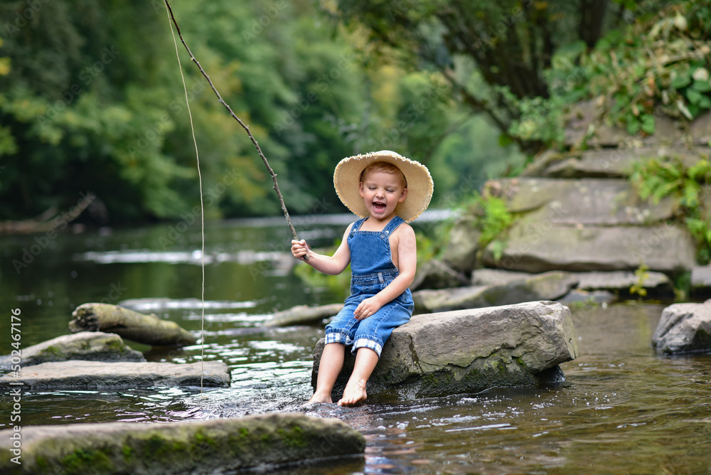 Foto de Funny happy little kid fishing on weekends. A fisherman's cub ...