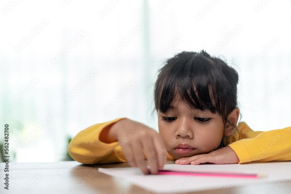 Little Asian girl sitting alone and looking out with a bored face ...