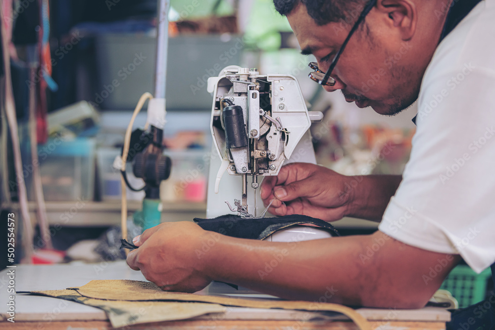 working process. Tanner or Skinner sews leather with a special sewing ...