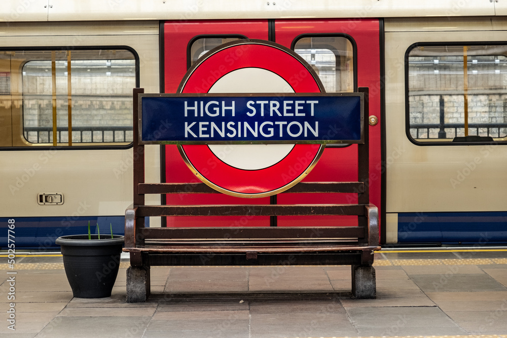 London- High Street Kensington underground station sign with train in ...