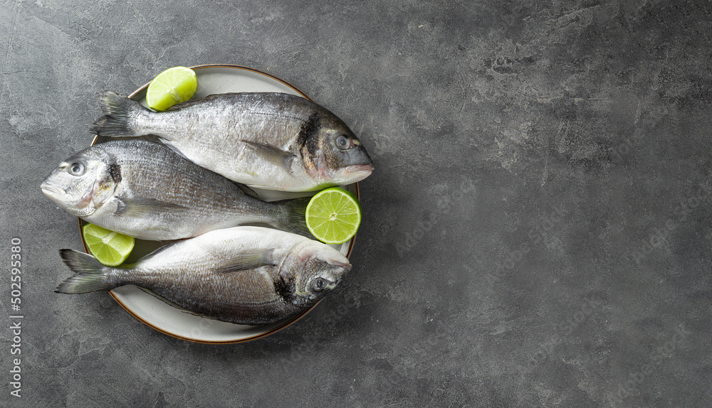Raw dorado fish with lime on the plate and on the grey background, top ...