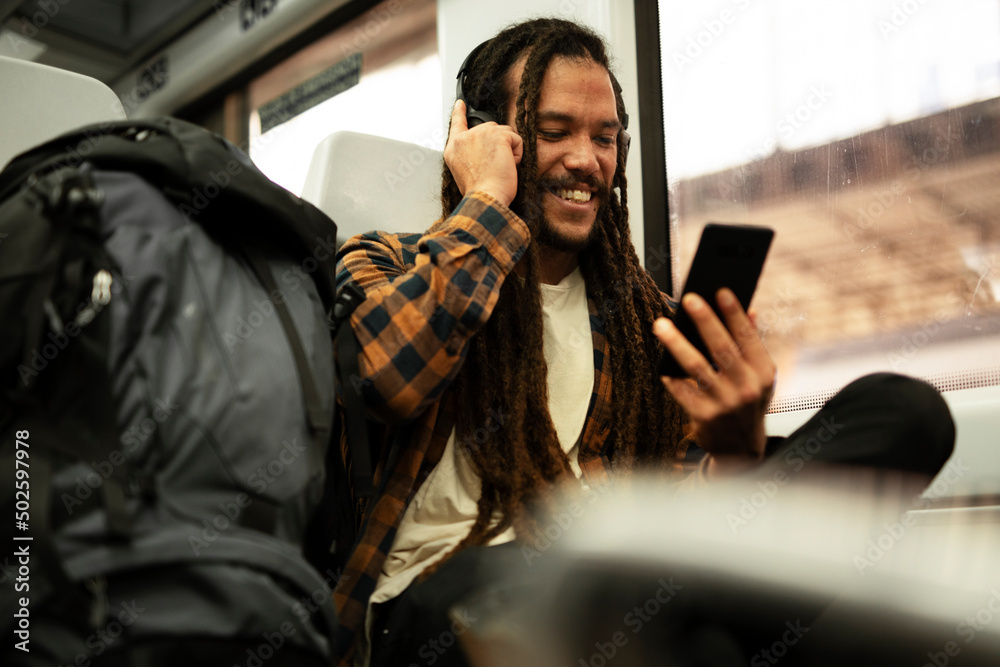 Young man listening the music while traveling by a train. Handsome ...
