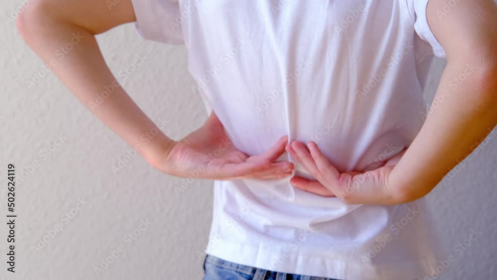 back of boy, child 8-10 years old in a white t-shirt grabbed a sore ...