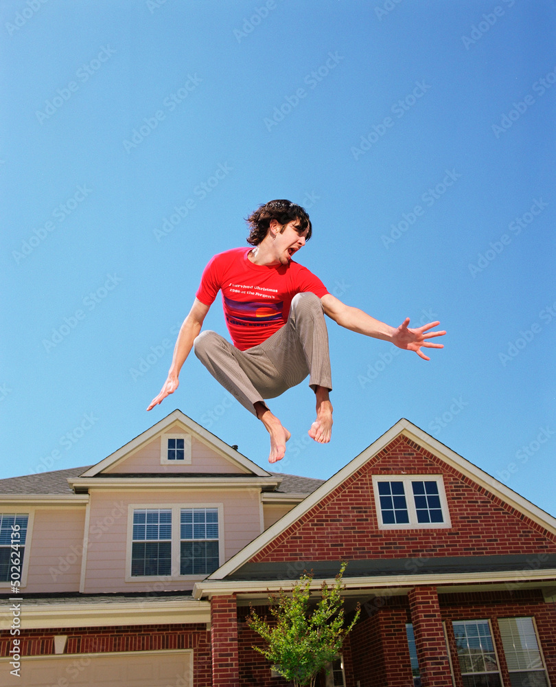 Teenage boy jumping in front of home, striking a pose mid air Stock ...