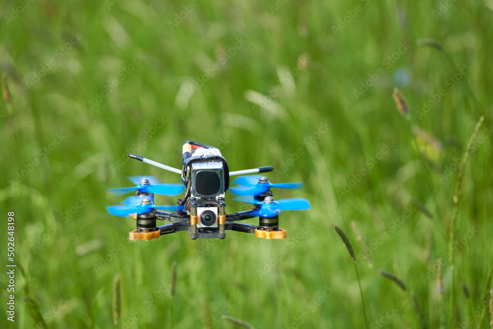 Small racing drone also quad copter with blue propellers and a big ...