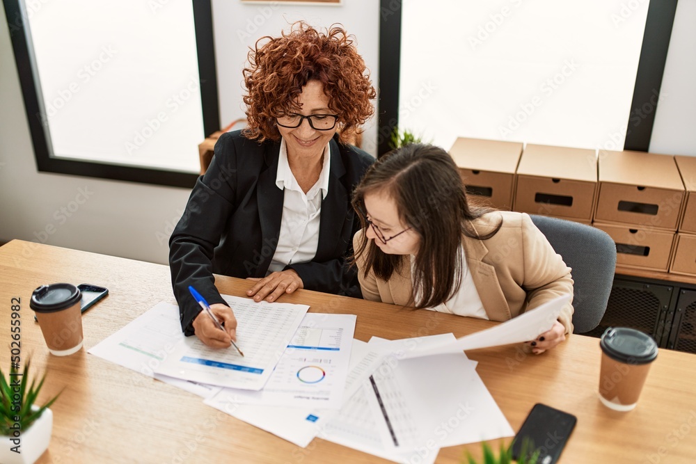 Group of two women working at the office. Mature woman and down ...