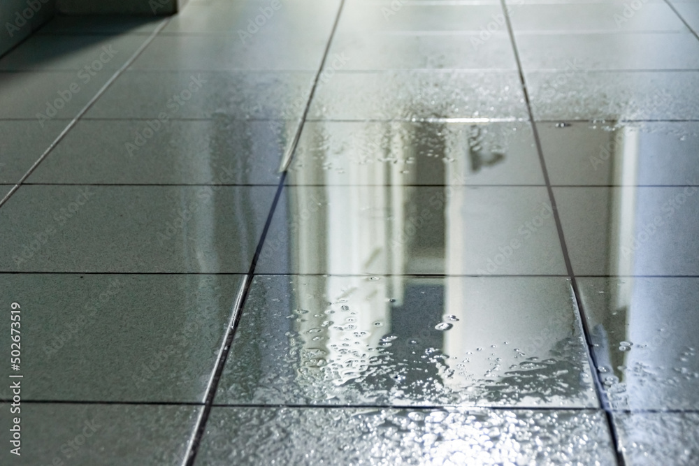 a large puddle on the tiled floor was caused by water from the ceiling ...