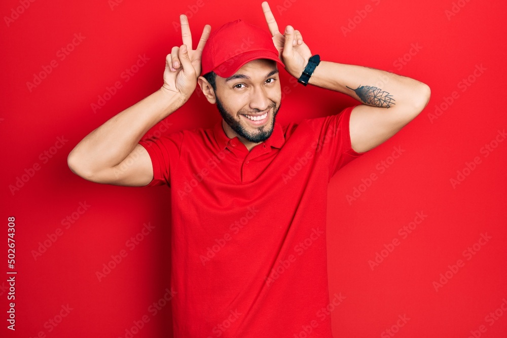Hispanic man with beard wearing delivery uniform and cap posing funny ...