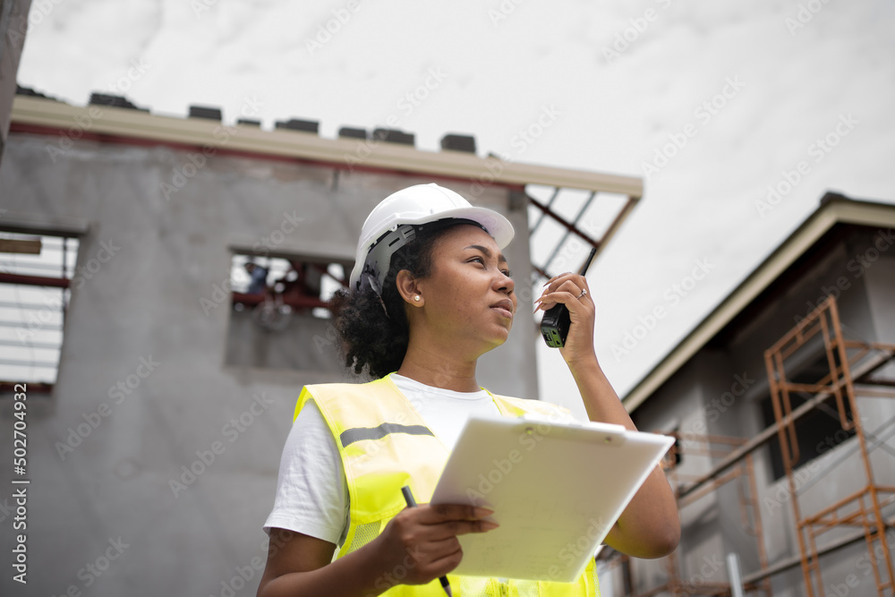 African female engineer using radio ordering work at construction ...