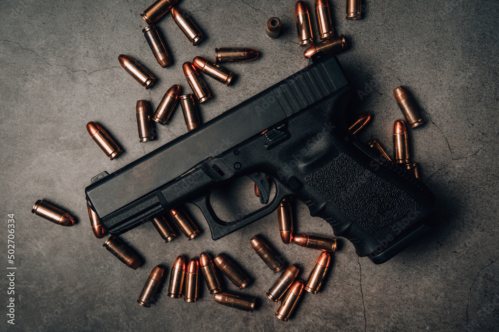 black 9mm pistol on an old concrete floor with 9mm ammunition next to ...