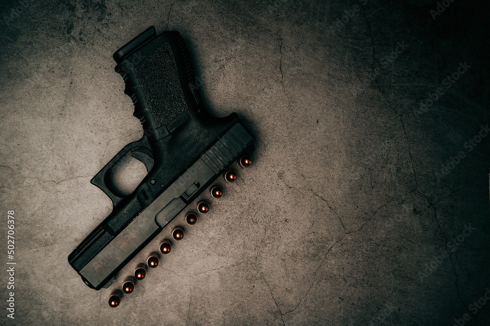 black 9mm pistol on an old concrete floor with 9mm ammunition next to ...
