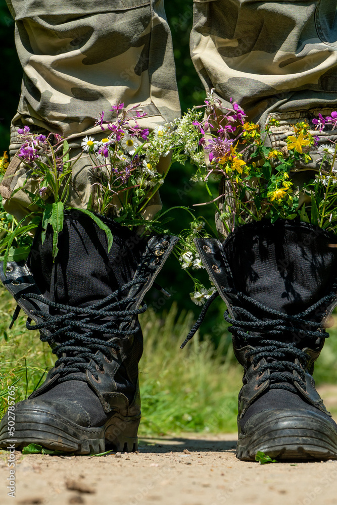 Black military boots with flowers. Concept - flowers instead of bullets ...