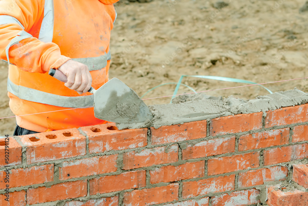 Bricklayer laying bricks on mortar on new residential house ...