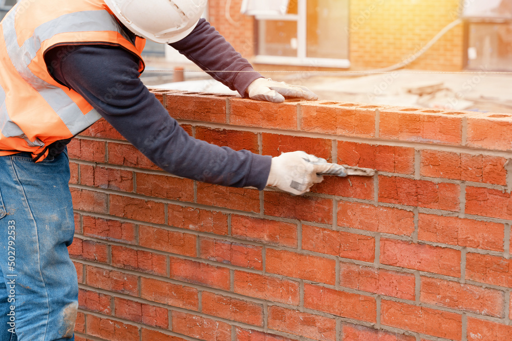Bricklayer laying bricks on mortar on new residential house ...