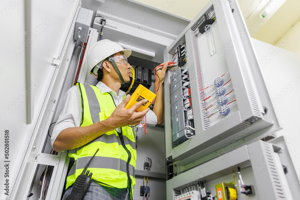 Poster Electrical engineer holding digital multimeter, Electrical ...