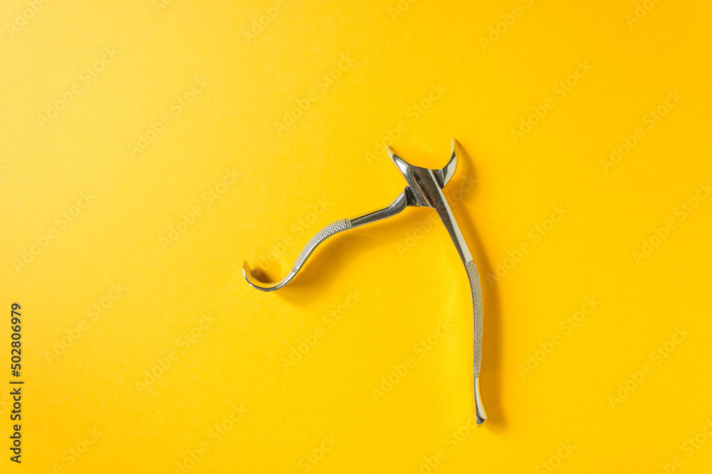 Dental extraction forceps isolated on the yellow background. For ...