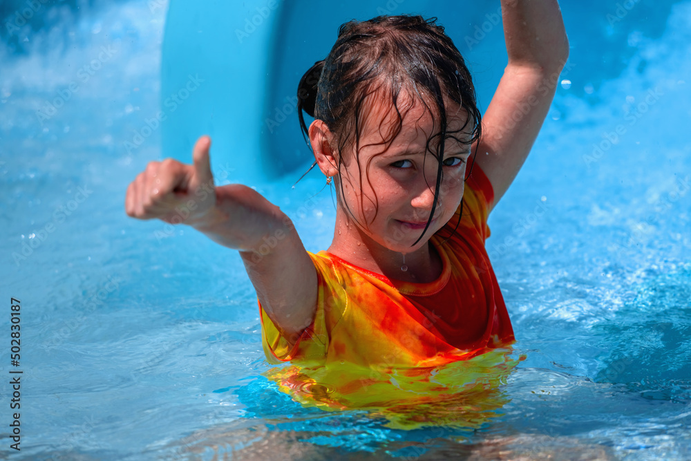 Young girl on water slide at water park raising hands and raising ...