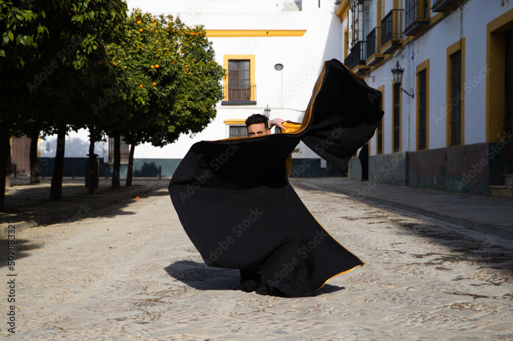 Portrait of young and handsome gipsy man, dressed in black and red shoes dancing with a black ...