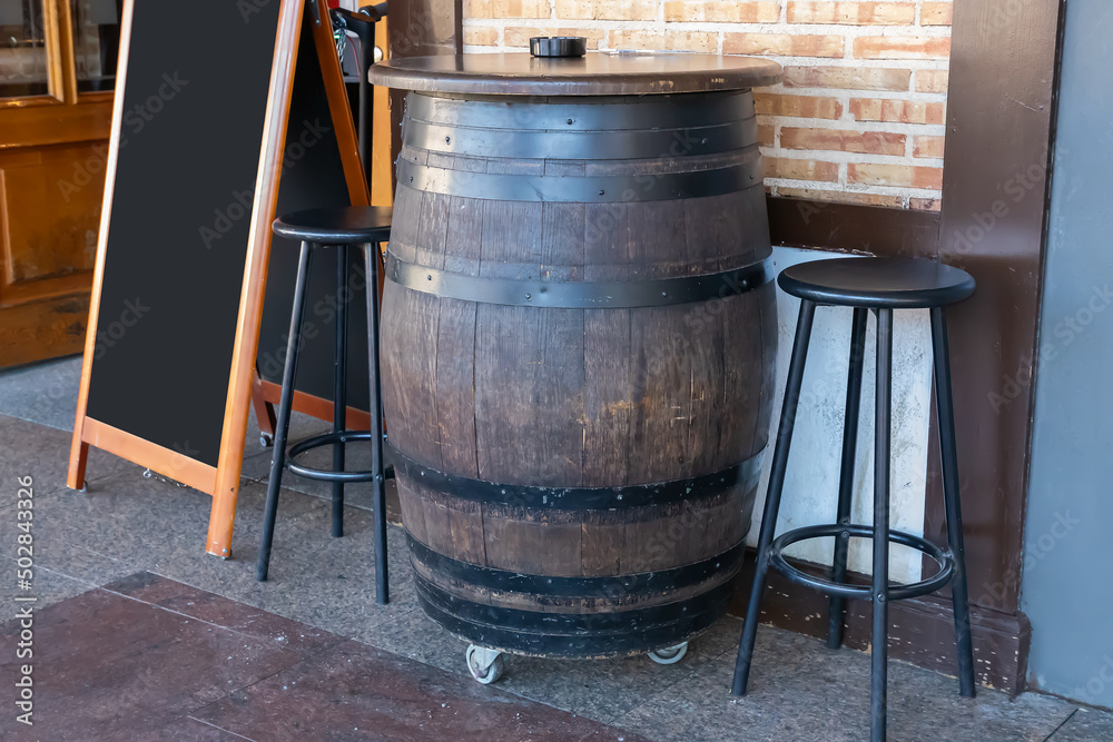 large wooden barrel used as a table and empty black restaurant menu ...