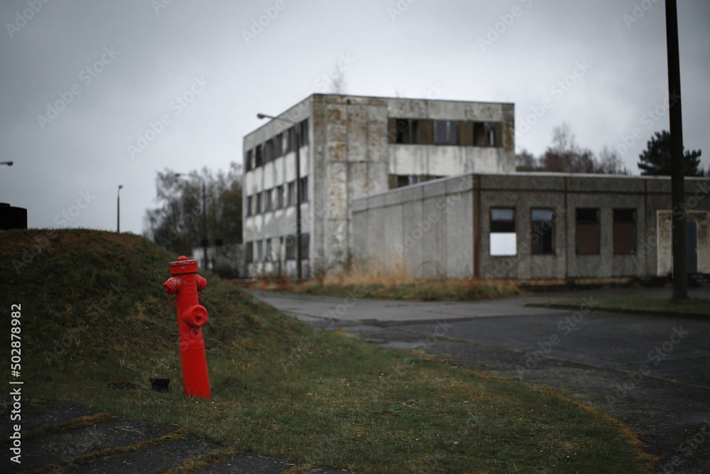 Foto de Vibrant red fire hydrant standing out in front of ruined ...