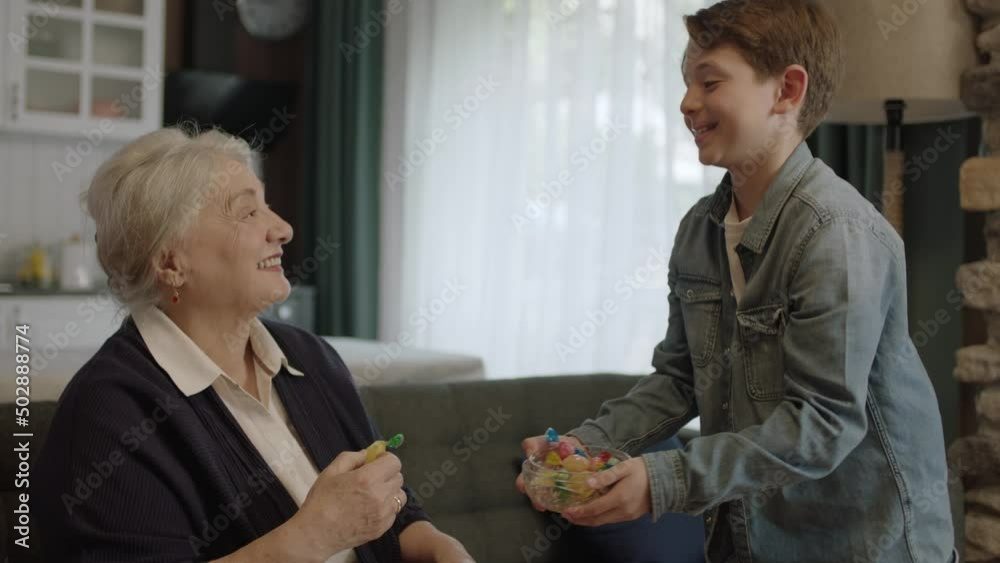 Boy offering candy in bowl to his elderly grandmother.Little boy ...