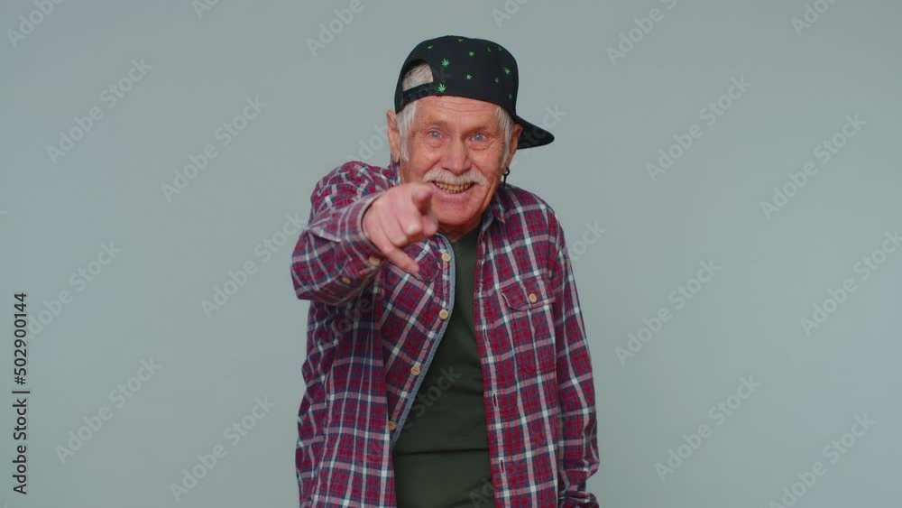 Amused senior man in casual shirt pointing finger to camera, laughing ...