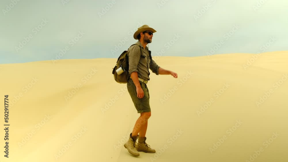 tourist in safari style walks through the sandy desert, leaving ...