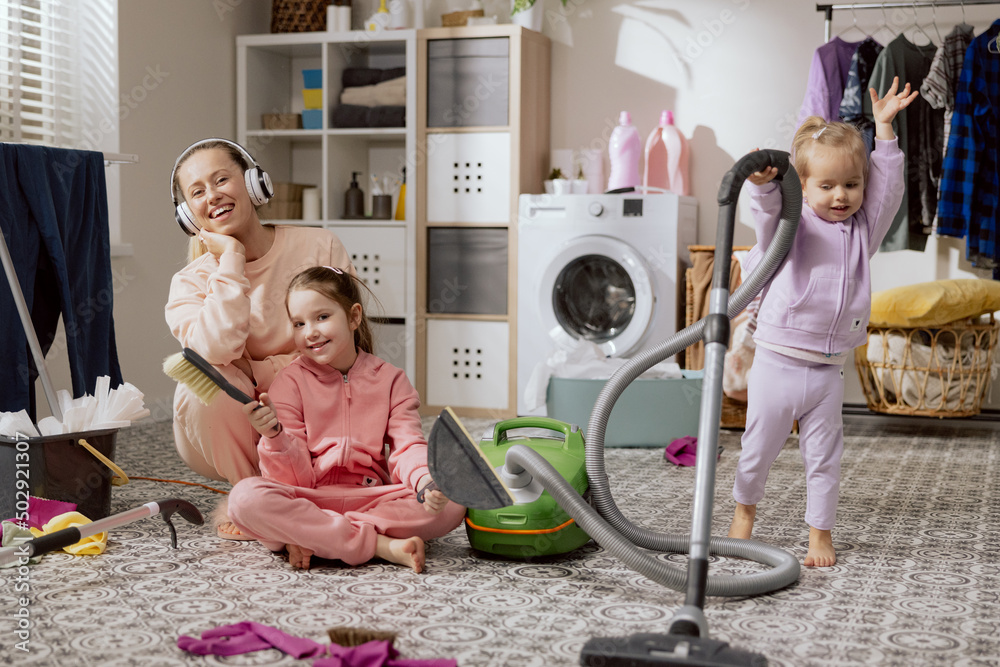 Happy family vacuuming a room. Mother and daughters cleaning house ...