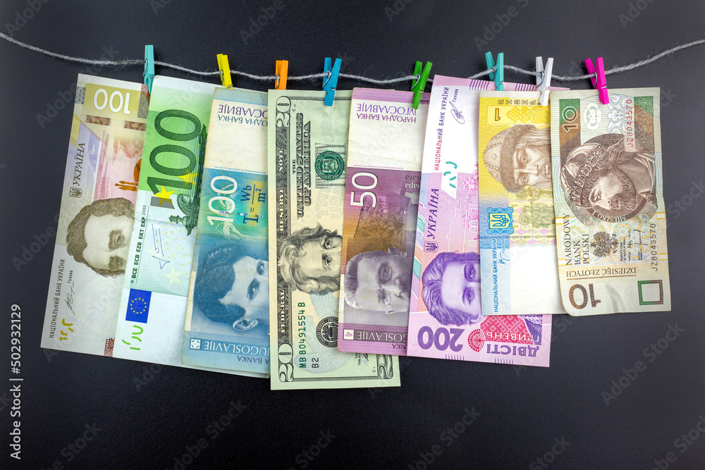 Paper money from different countries is hung on a rope with clothespins ...