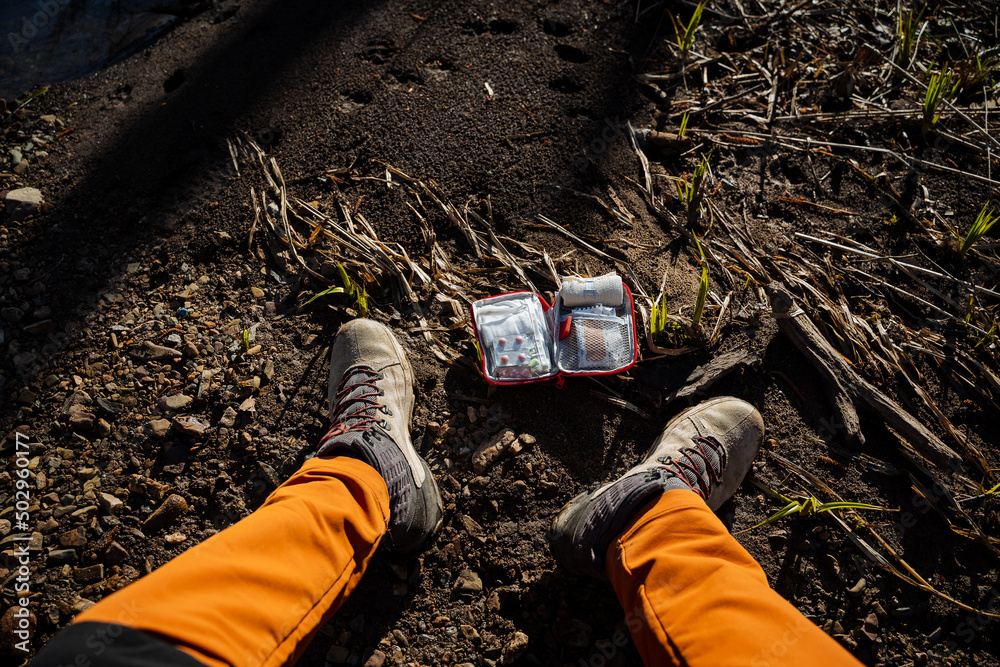 The open first aid kit lies on the ground at the feet of the tourist. A ...