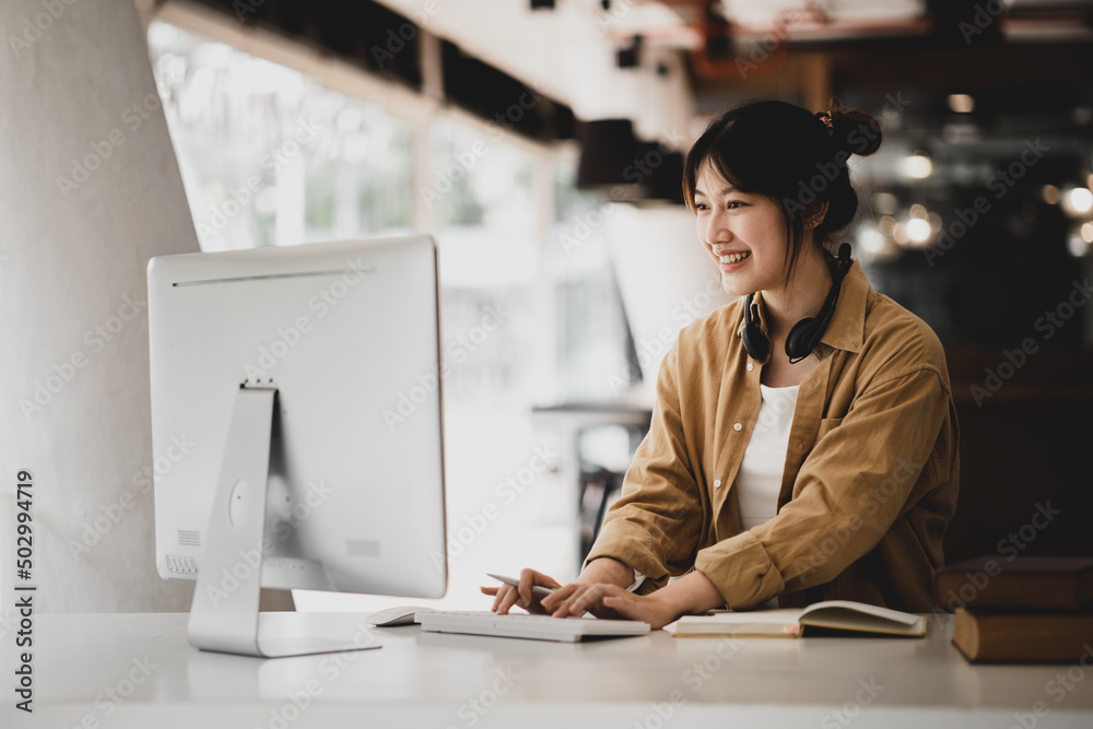 Asian woman using a computer to study online Stock Photo | Adobe Stock