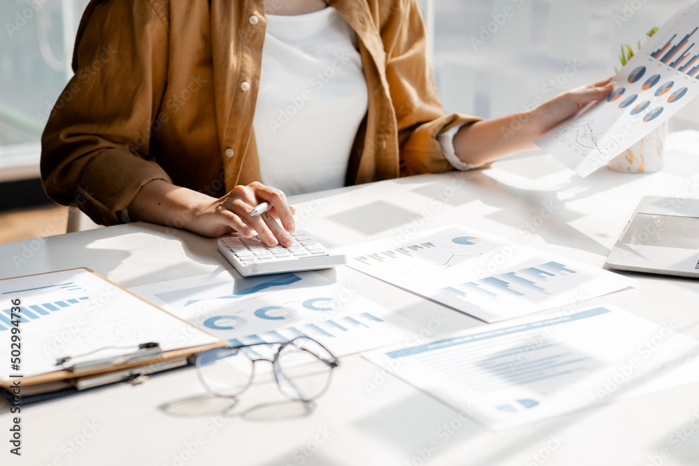 A business finance woman is reviewing a company's financial documents ...