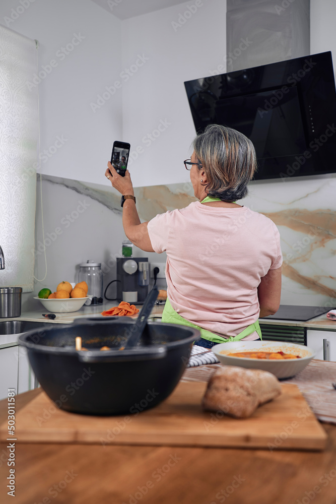 Adult woman, cooking a Spanish dish, estofado de albóndigas. Taking a ...