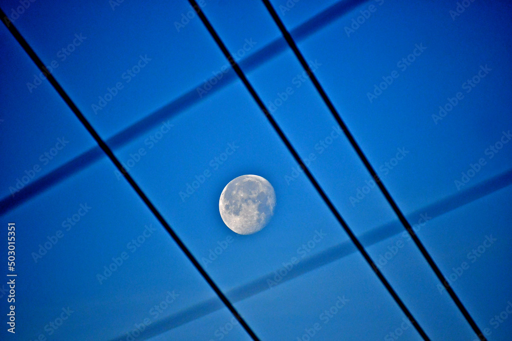 Power lines frame the moon between the phases; full moon and waning ...