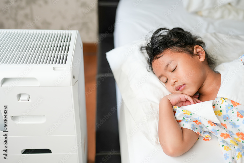 Sleeping Asian girl laying in bed next to Air Purifier. Clean Air ...