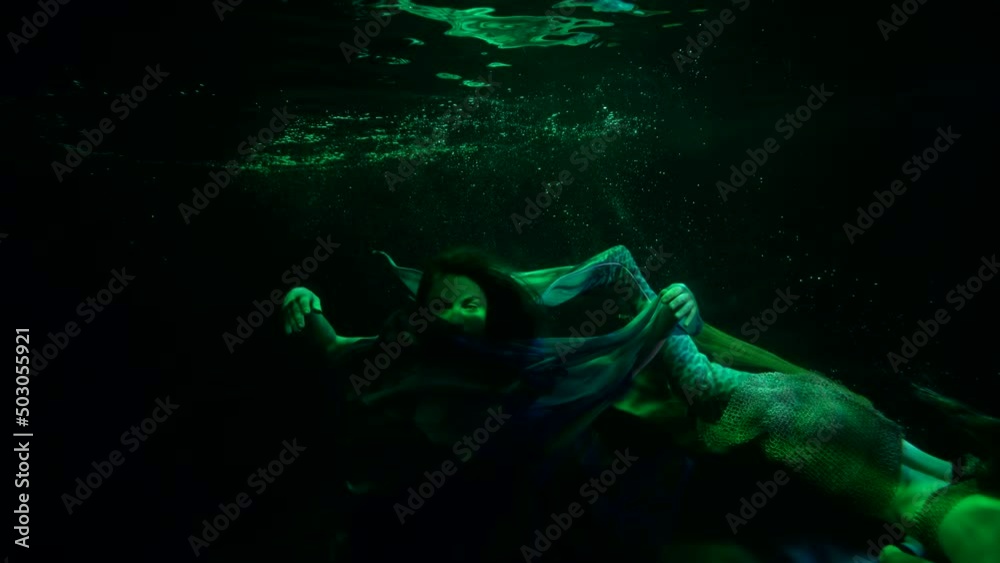 two mermaids are swimming in mysterious dark of ocean depth, slow ...