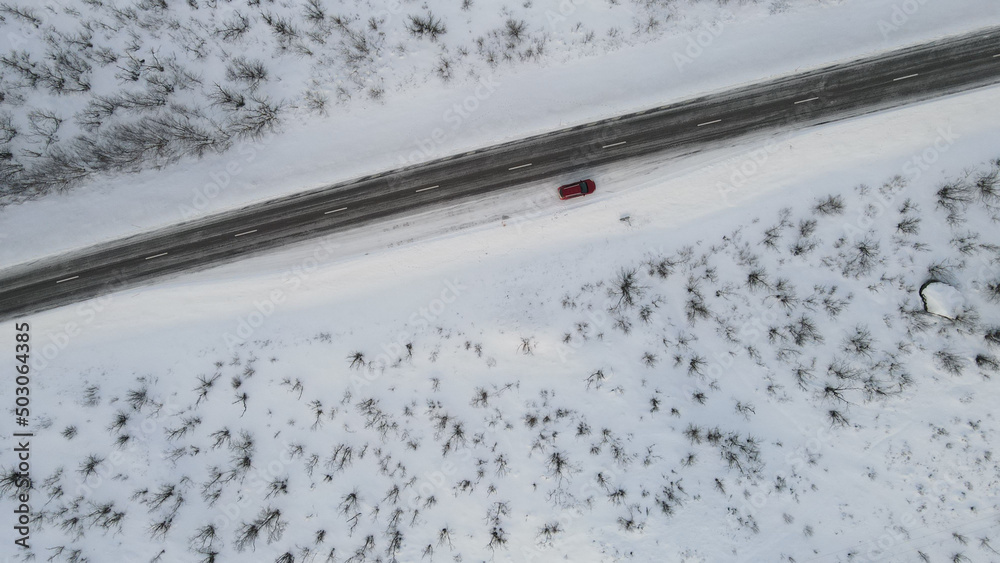 Aerial view of a vehicle on an asphalt road cutting through fields ...