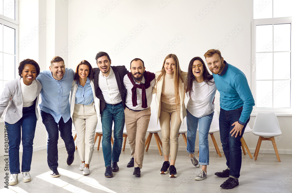 Team of young and successful multiracial people hug and smile at camera ...