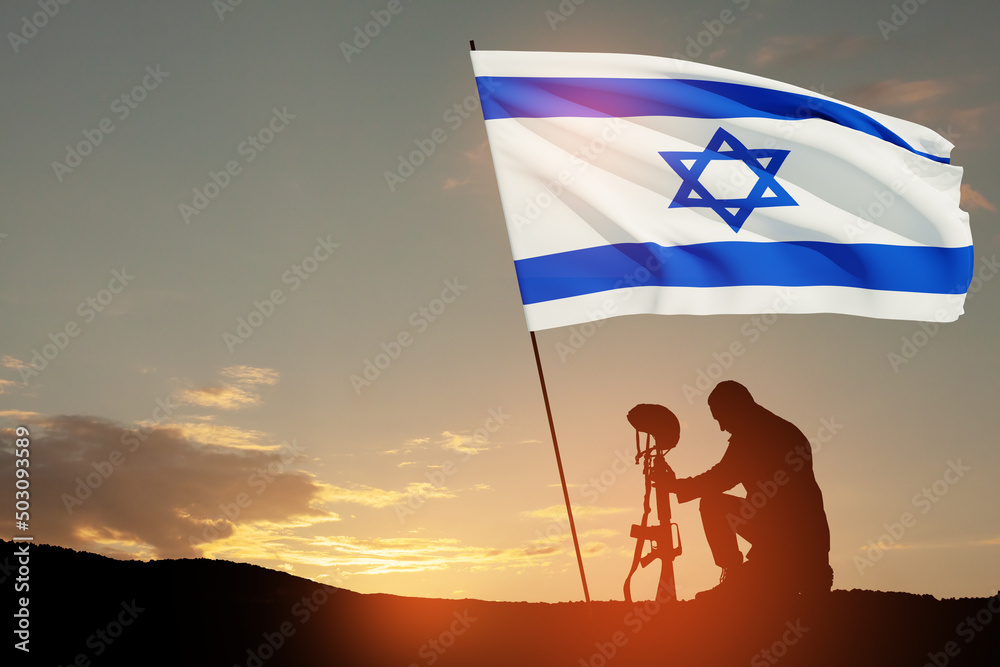 Silhouette of soldier kneeling with his head bowed with Israel flag ...