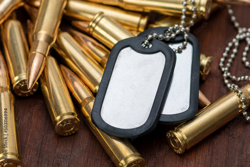Army identification tokens lie on scattered yellow machine gun ...