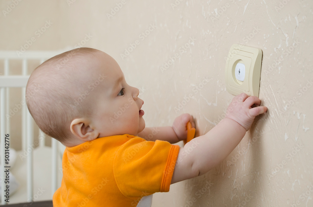 A curious baby touching an electrical outlet. Danger at home for ...