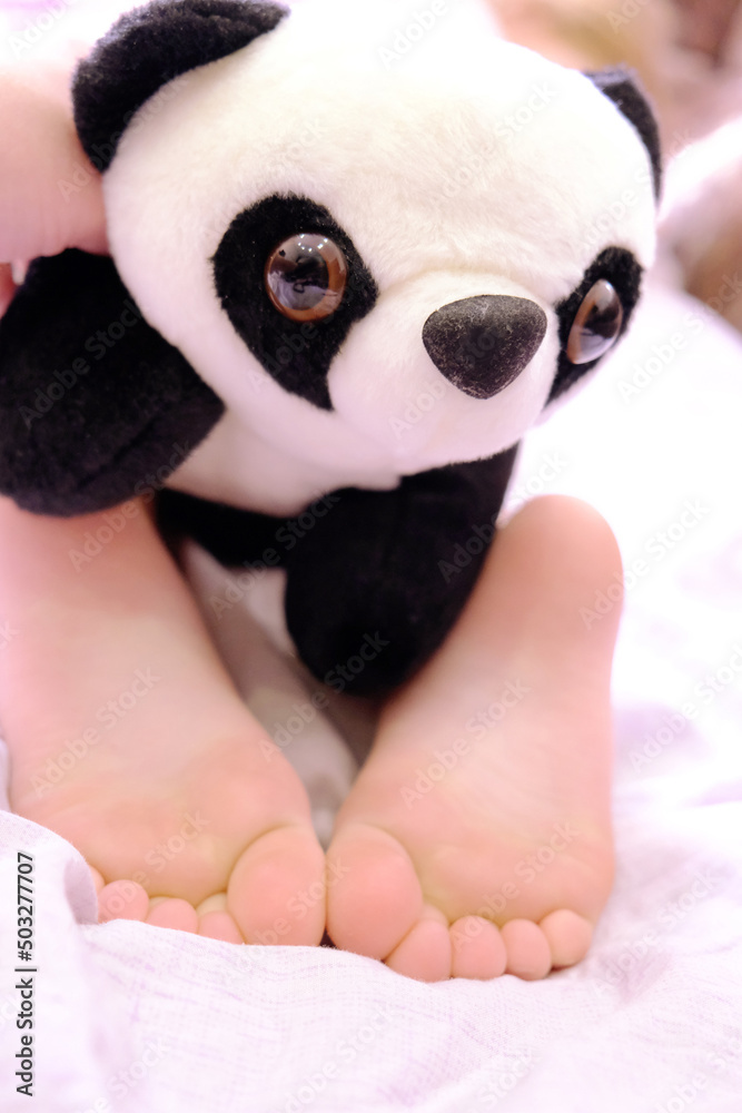 Bare feet, relaxing with panda toy. Lazy holiday concept. Waking up ...