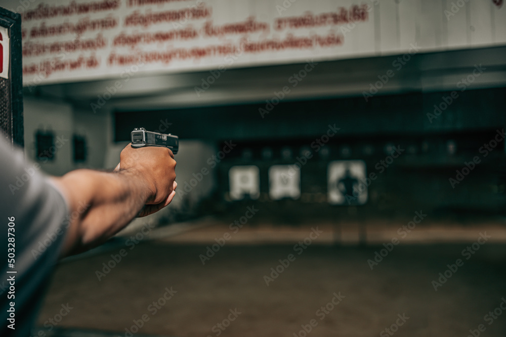 Professionals practice shooting a 9mm pistol inside a shooting range ...